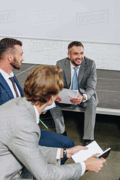 smiling handsome business coach looking away during training in hub ...