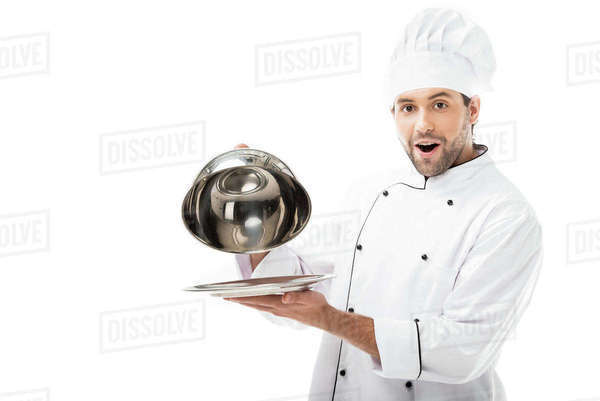 Excited young chef taking of serving dome from plate and looking at ...