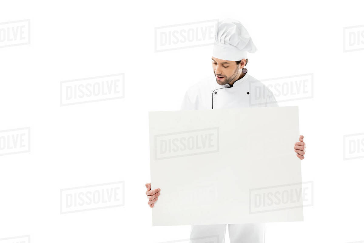 Professional young chef holding blank banner and looking down isolated ...