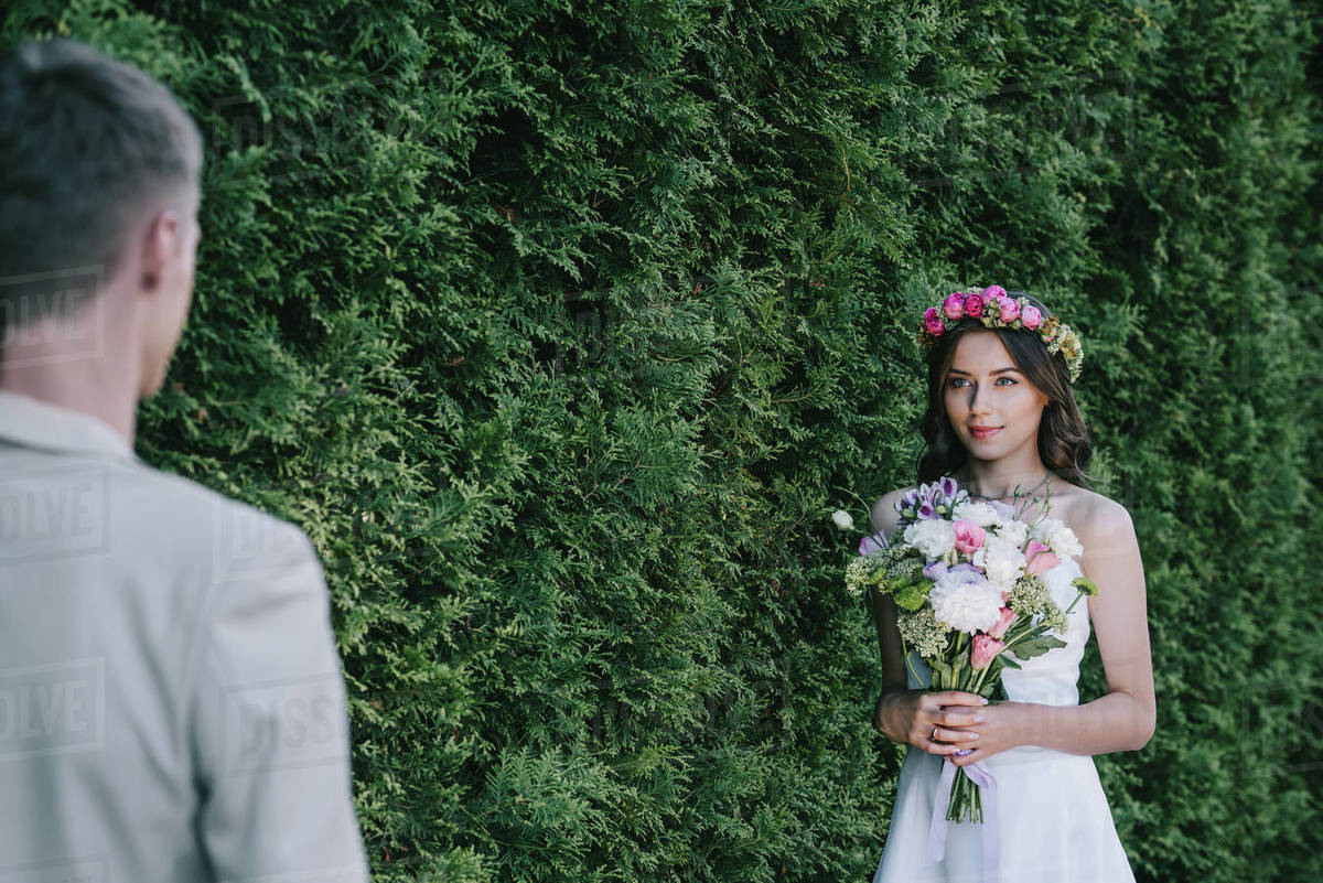 Selective focus of beautiful bride in wreath with wedding bouquet ...