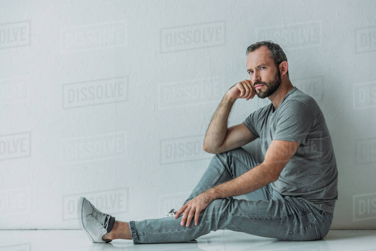 Side view of sad middle aged bearded man sitting on floor and looking ...