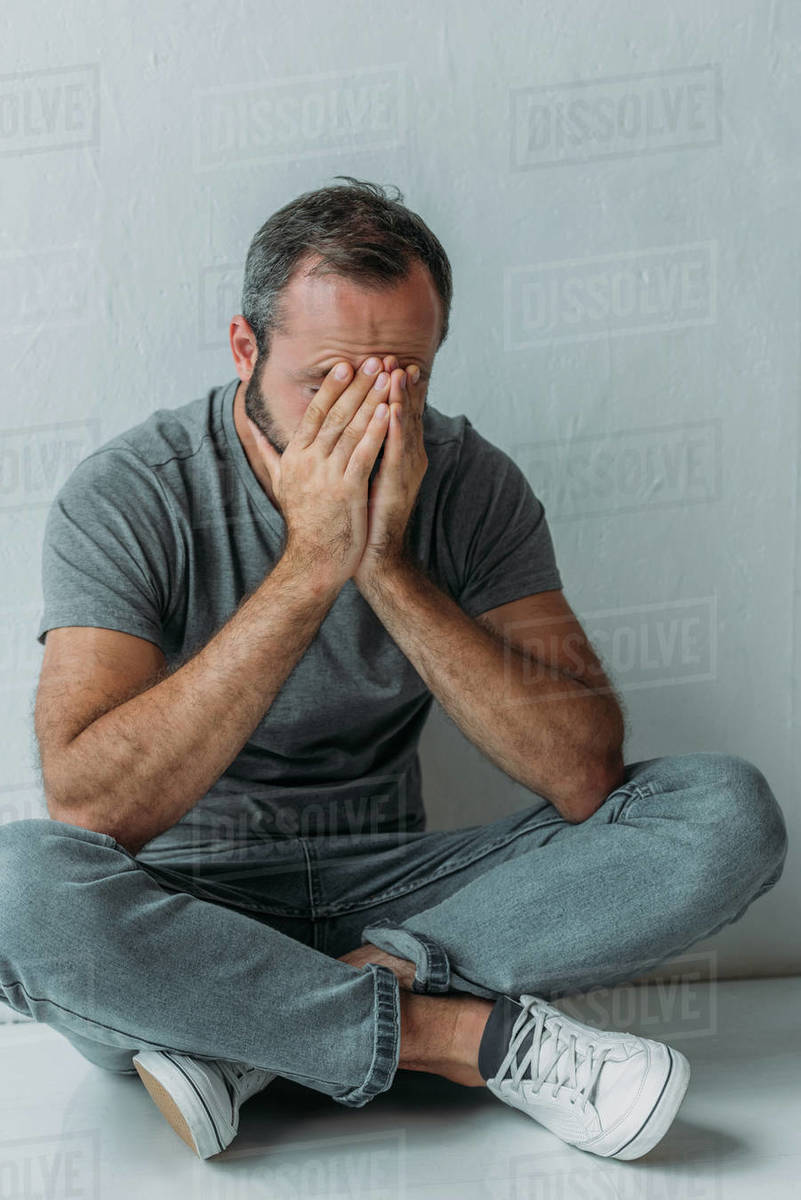 High angle view of stressed middle aged man sitting with hands on face ...