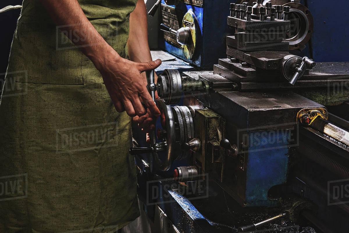 Cropped image of male manufacture worker in protective apron using ...