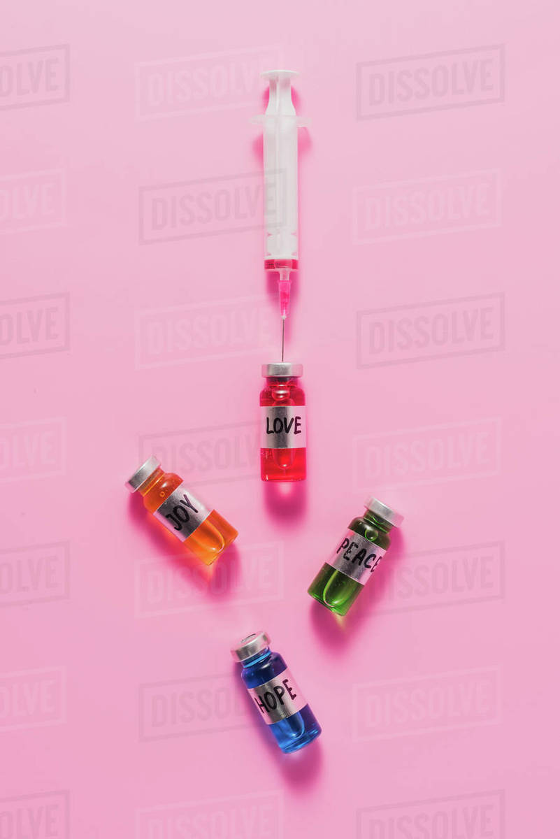 Top view of syringe and bottles with love, hope, joy and peace vaccine ...