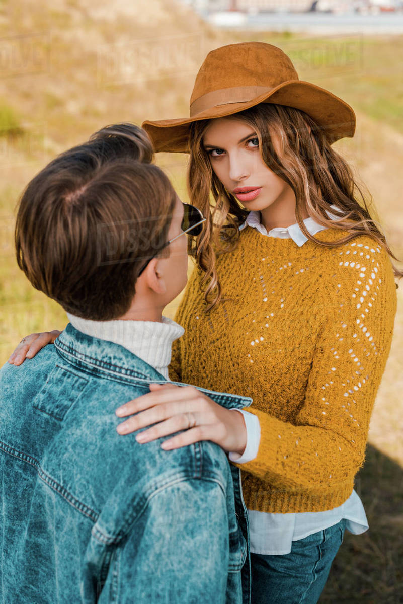 Beautiful girlfriend looking at camera and hugging boyfriend on meadow ...