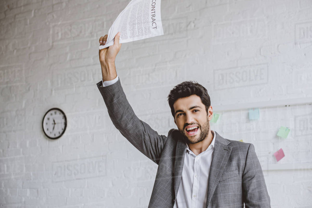 Happy handsome businessman holding documents in raised hand in office ...