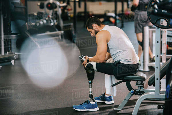 Overworked young sportsman with artificial leg sitting at gym - Royalty ...