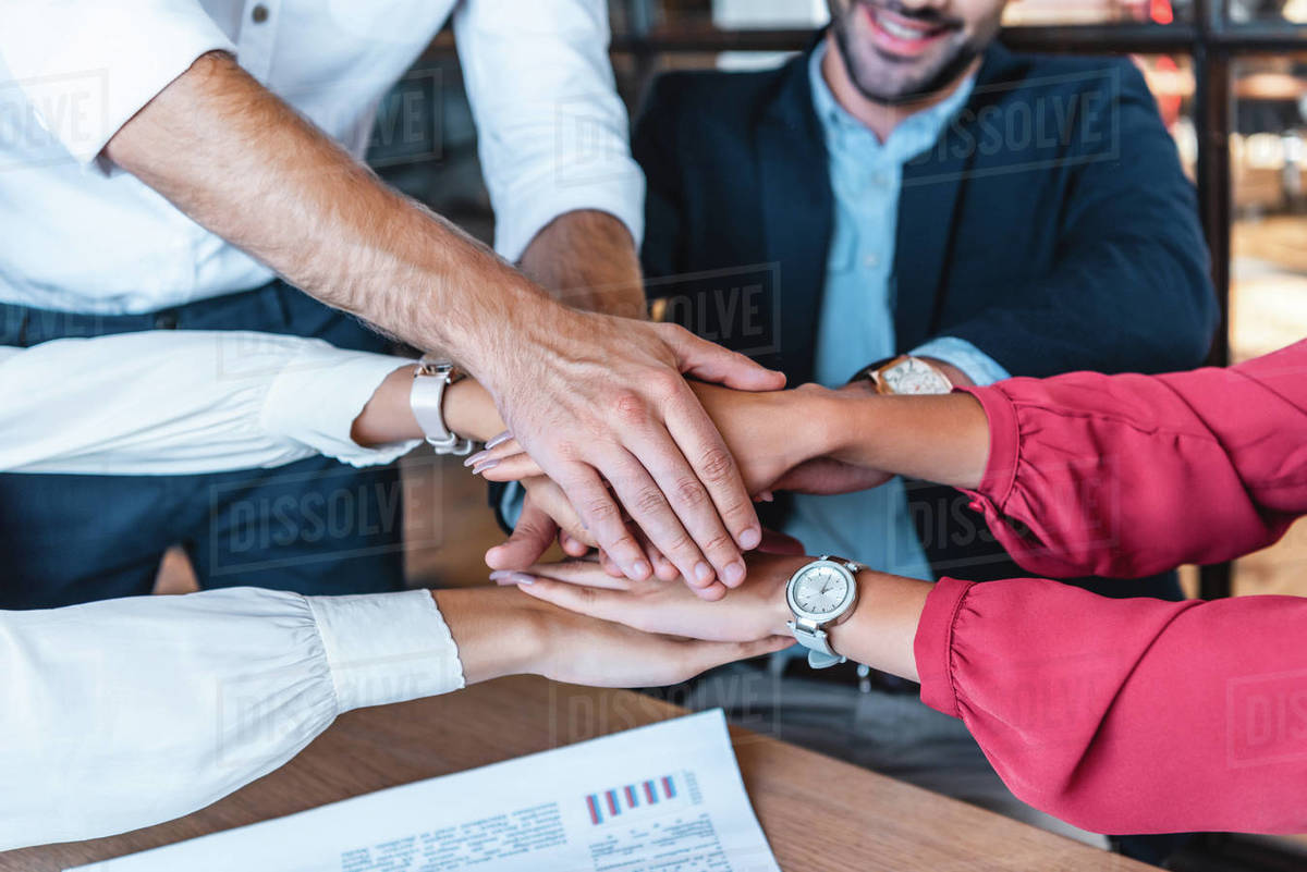 Cropped shot of business team holding hands at workplace in office ...