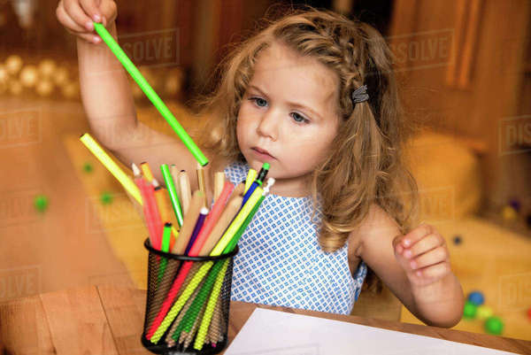 Adorable child taking green felt tip pen for drawing in kindergarten ...