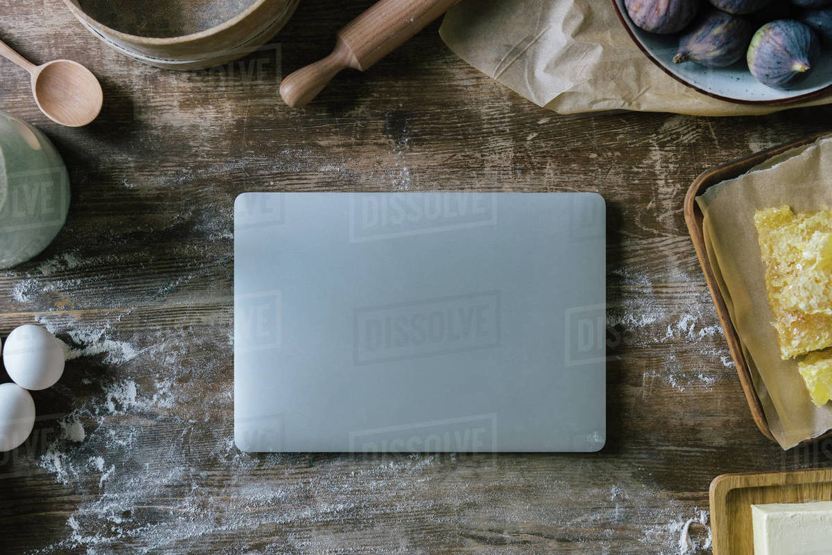 Top view of laptop on messy wooden table with spilled flour and baking ...