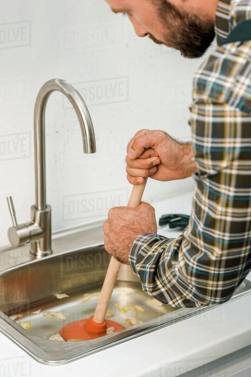Bearded plumber using plunger and cleaning sink in kitchen - Royalty ...