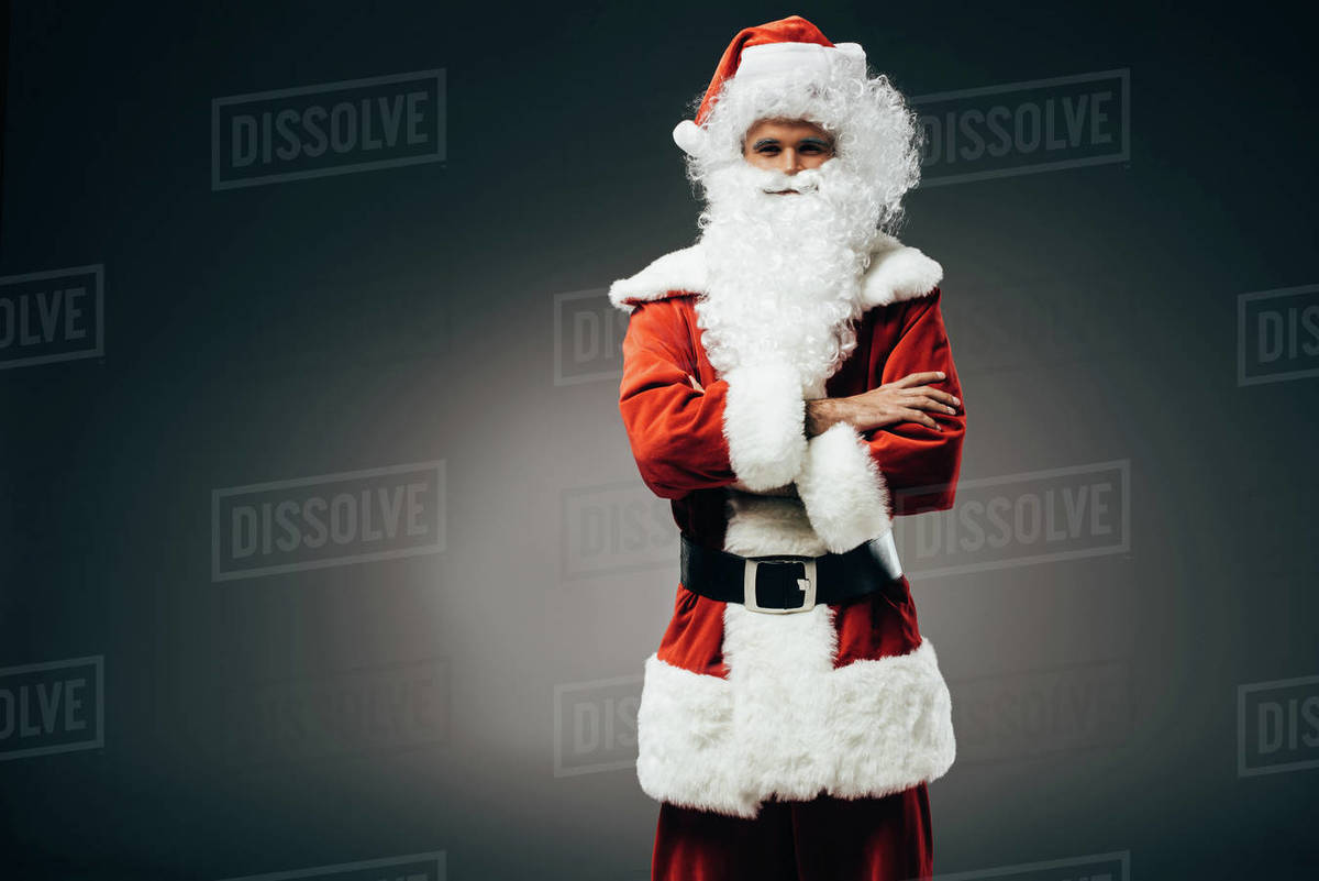 Santa Claus in costume standing with crossed arms isolated on grey ...