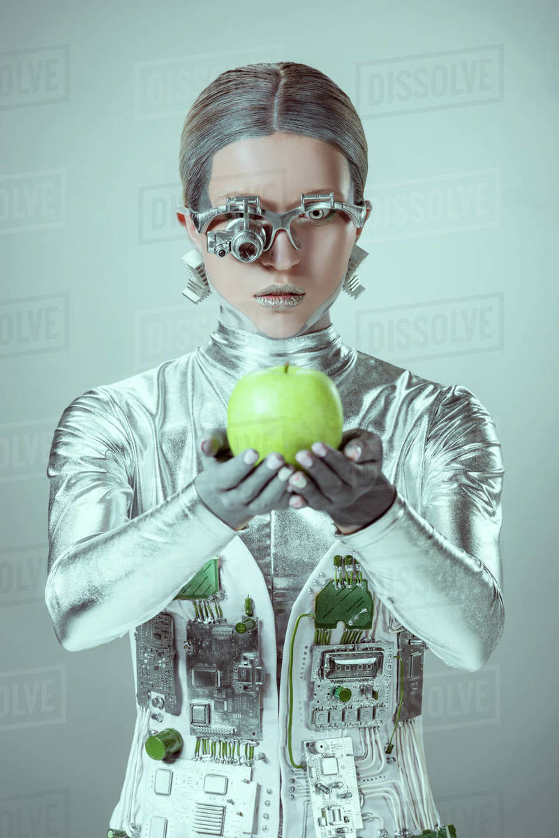 Cyborg holding green apple and looking at camera isolated on grey ...