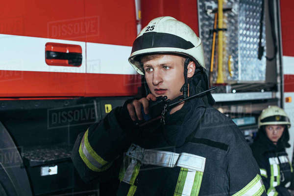 selective focus of firefighter in uniform talking on portable radio set ...