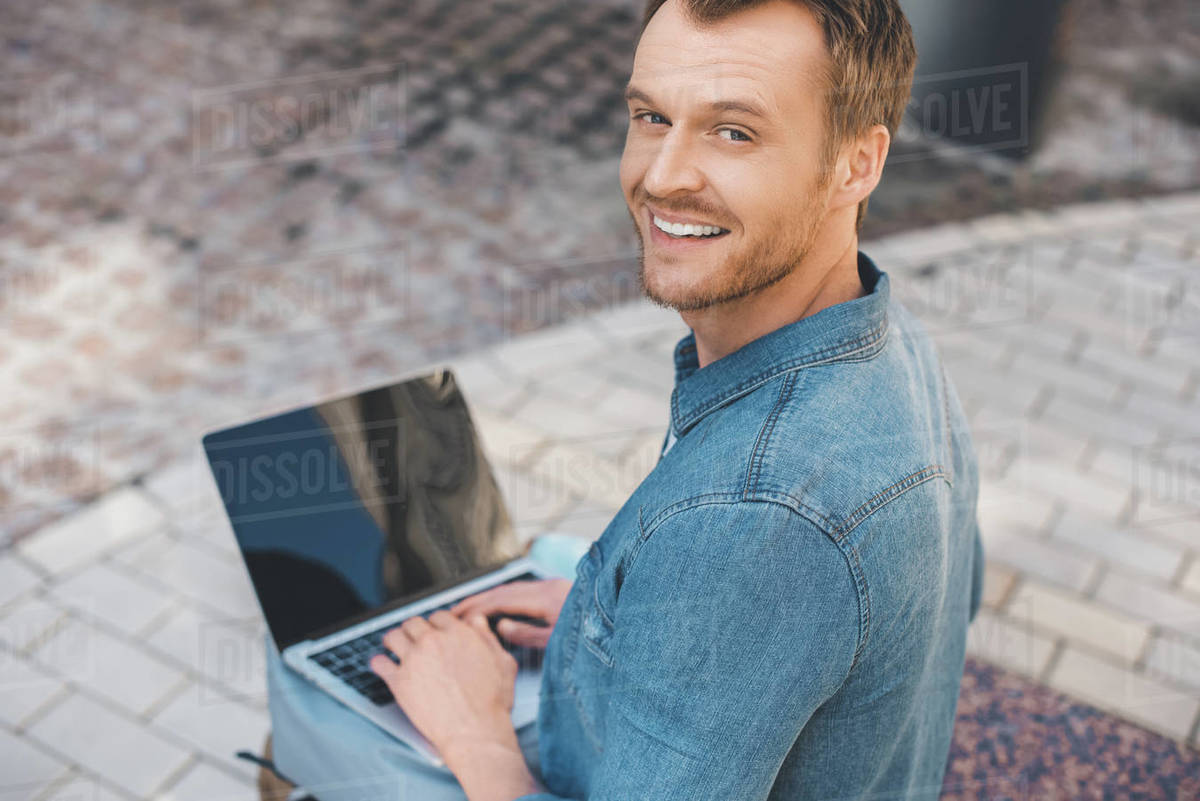 High angle view of handsome young man using laptop with blank screen on ...