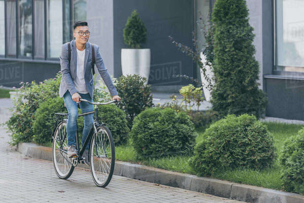 Stylish smiling Asian man cycling on bicycle in city - Stock Photo ...