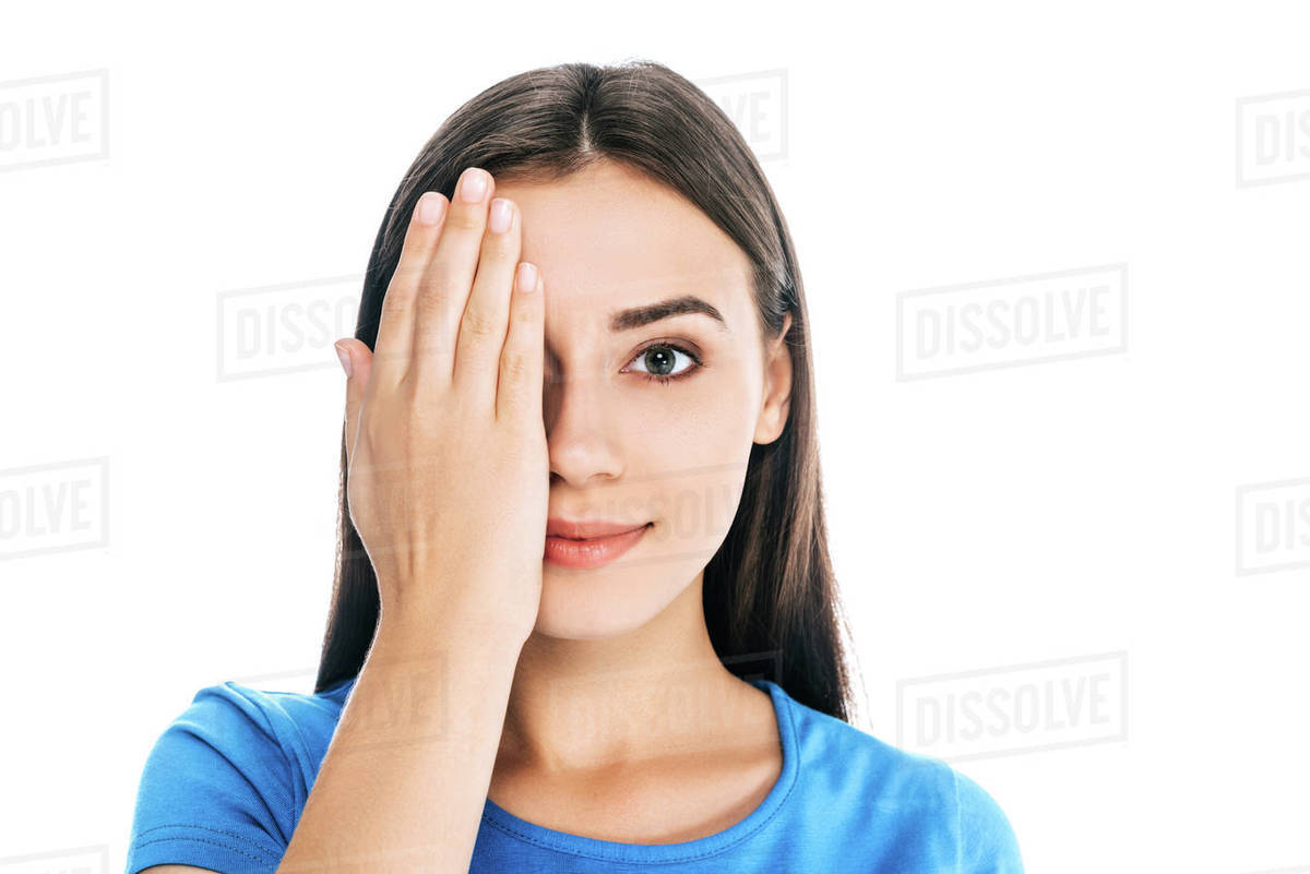 Obscured view of smiling woman covering eye with hand isolated on white ...