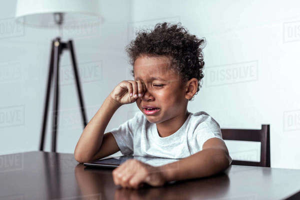 Little African American boy crying while sitting with digital tablet ...