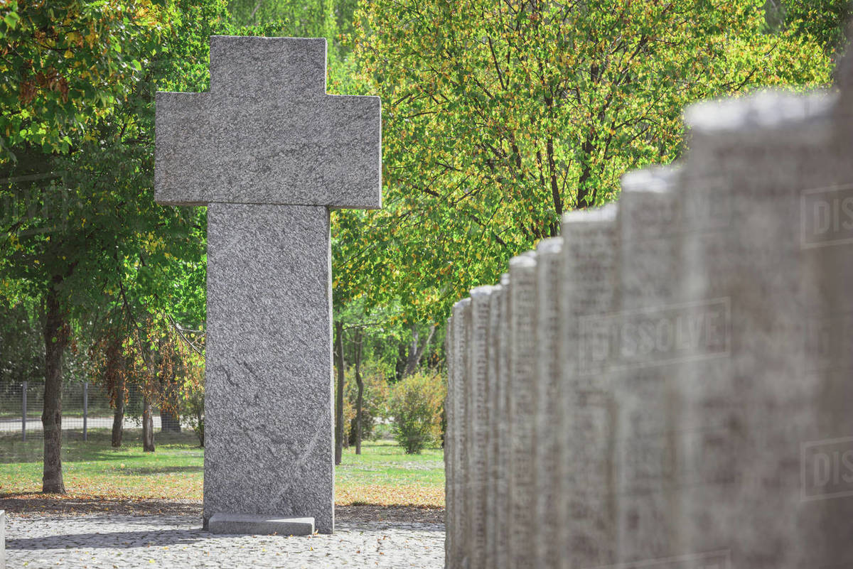 selective focus of old memorial monument in shape of cross at cemetery ...