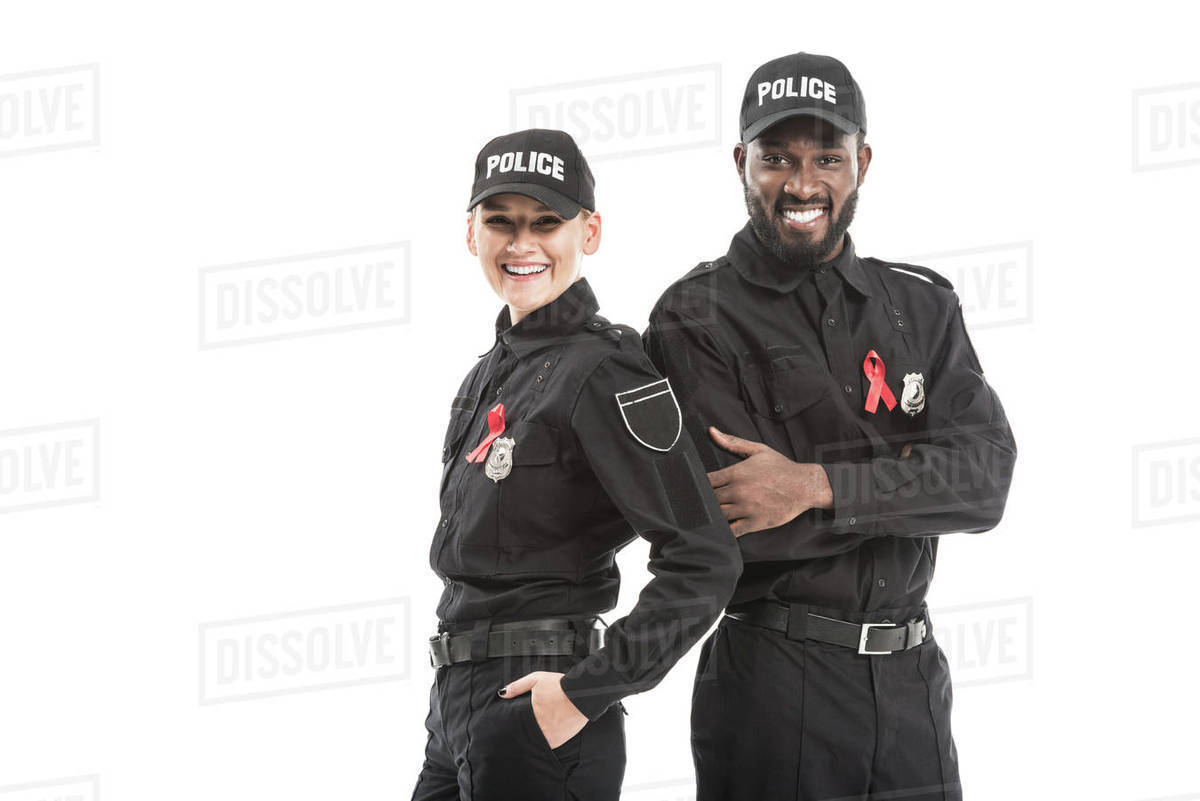Confident police officers with aids awareness red ribbons looking at ...