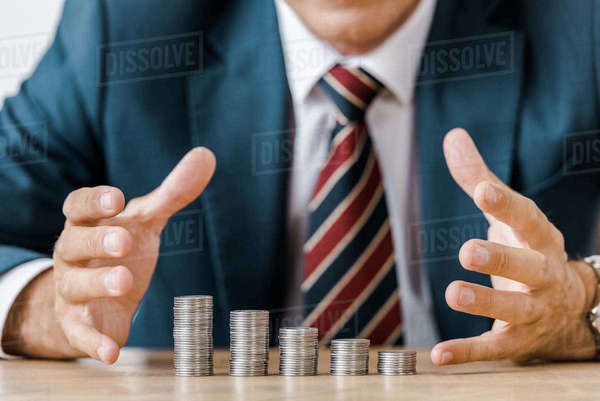 Businessman grabbing silver coins at wooden table - Royalty-free Stock ...