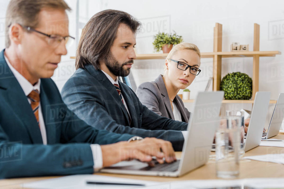 Insurance workers sitting at table and using laptops in office - Stock ...