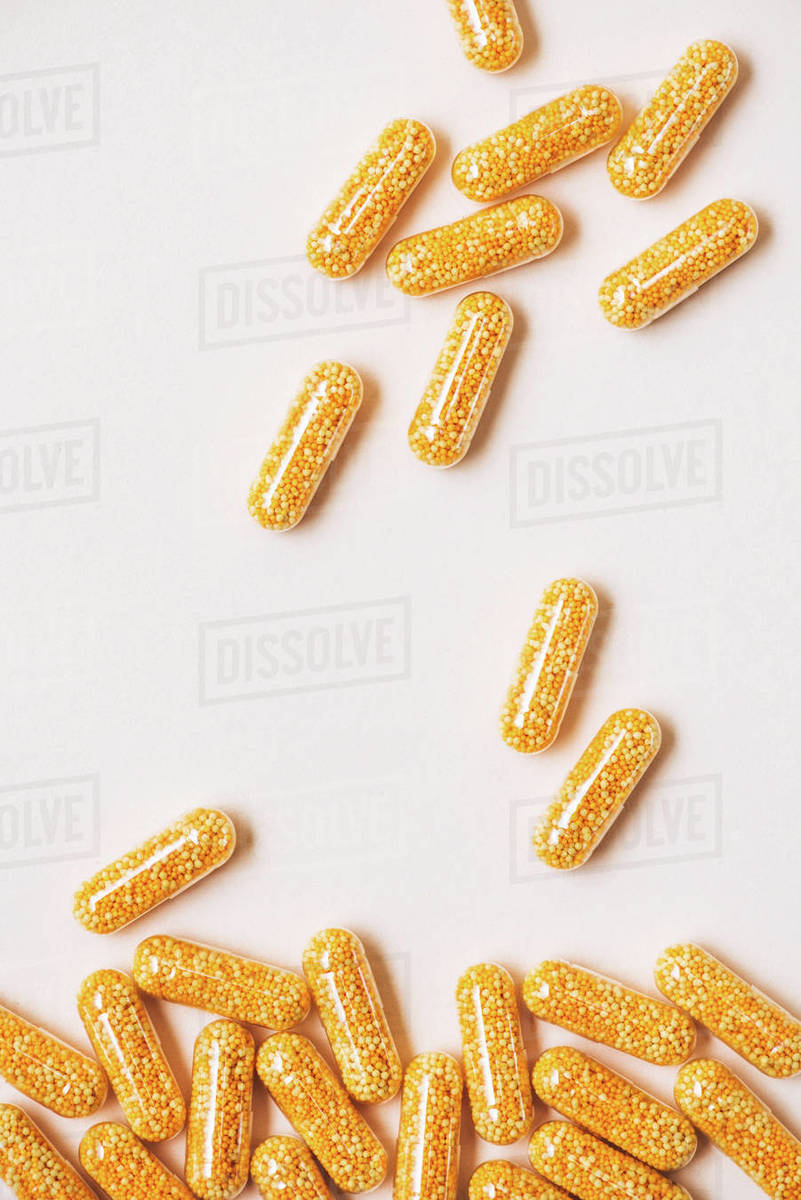 Top view of yellow medical capsules on white - Stock Photo - Dissolve
