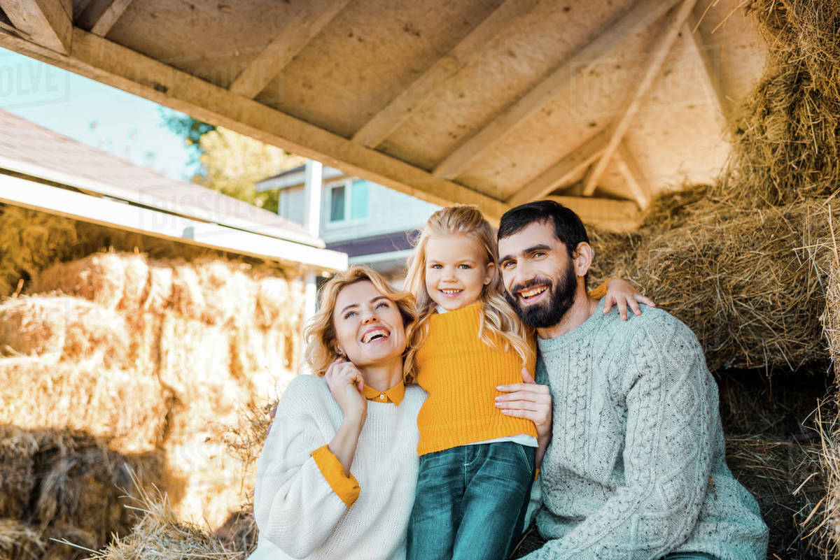 Selective focus of happy farmer family with child embracing each other ...