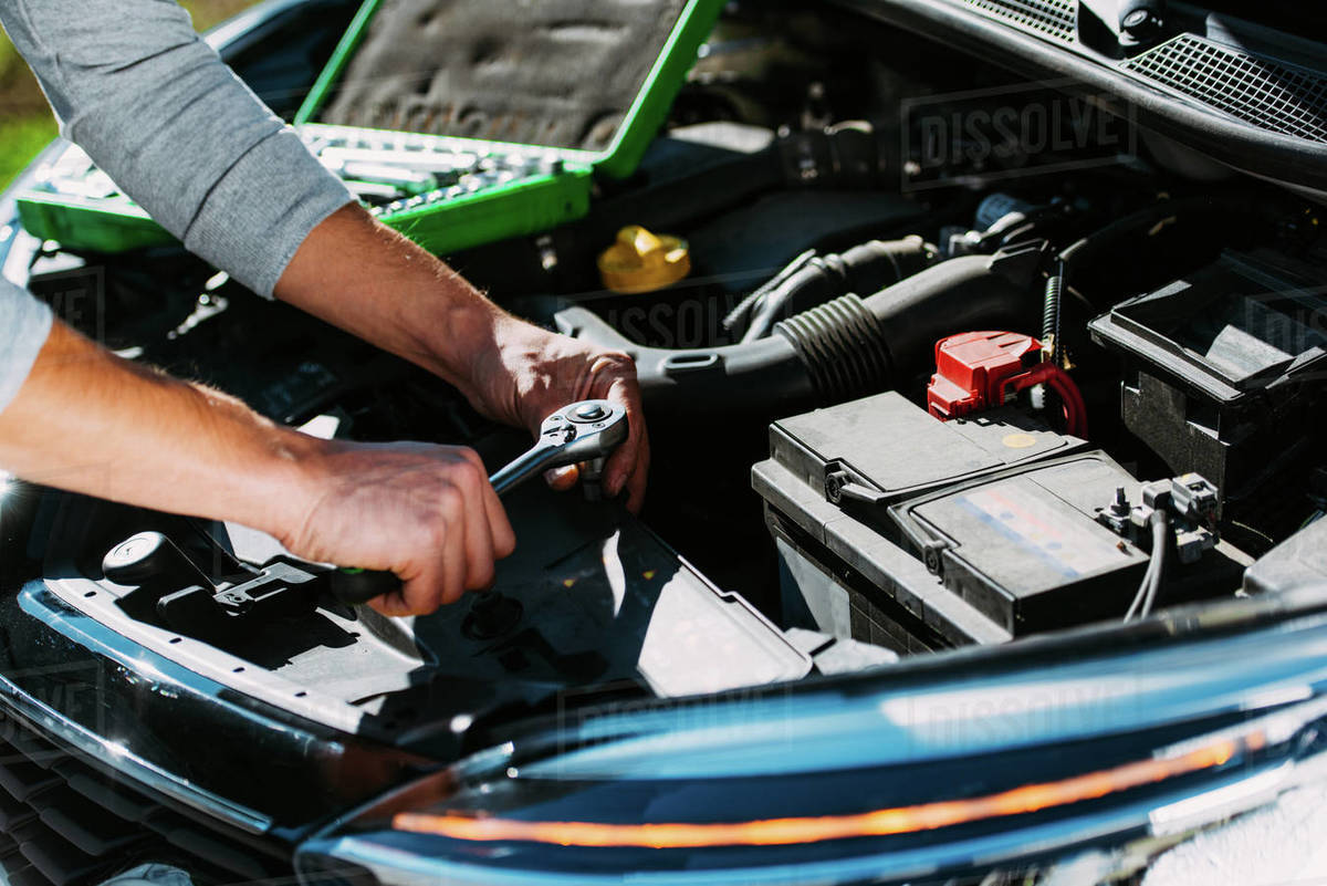 Close-up partial view of young man fixing broken car engine - Royalty ...