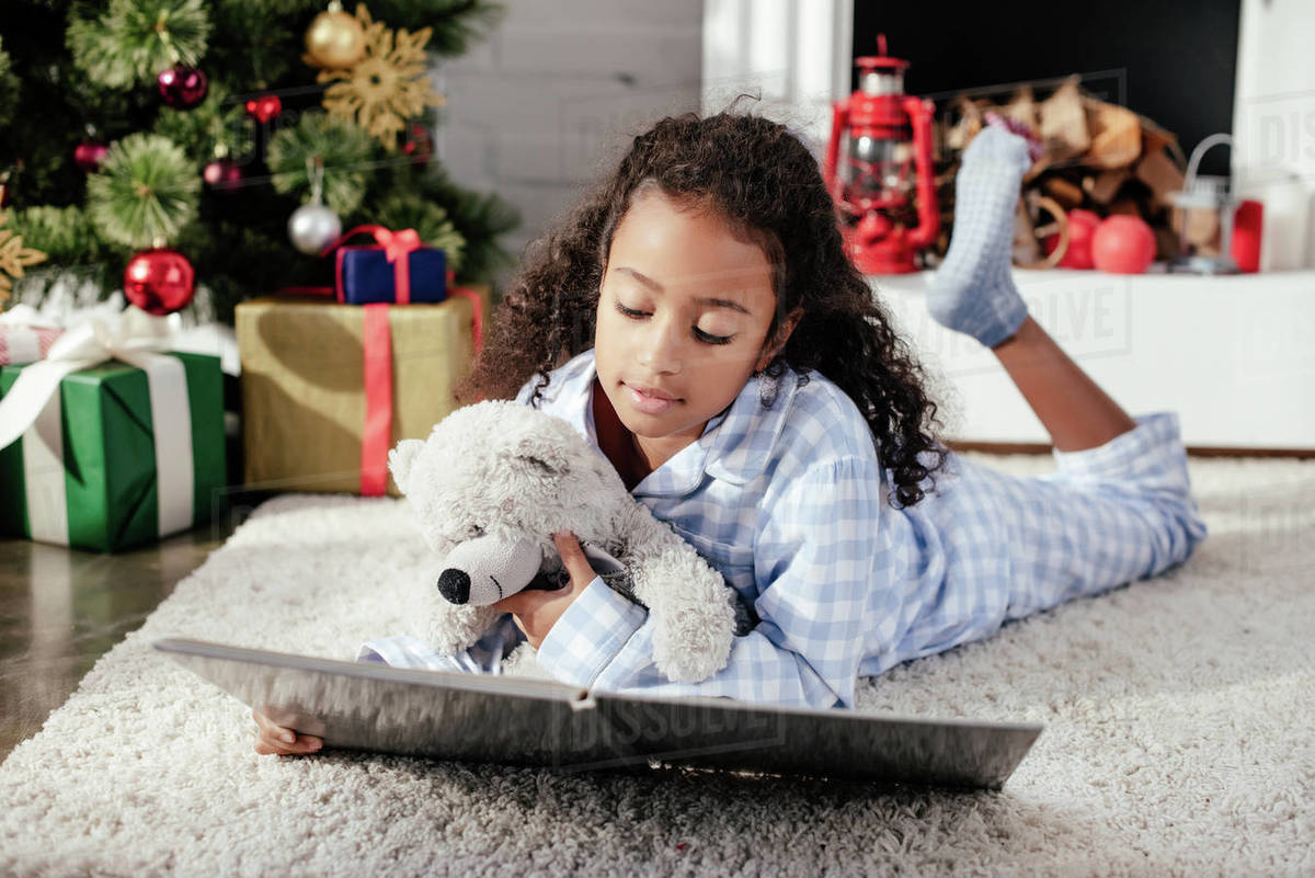 adorable african american child in pajamas with teddy bear reading book ...