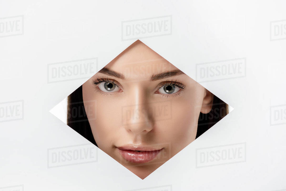beautiful young woman looking at camera through rhombus shaped hole on ...