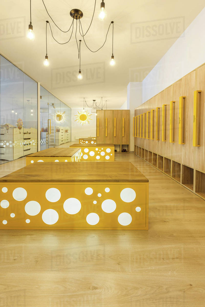 wooden lockers, benches and mirror in illuminated kindergarten ...