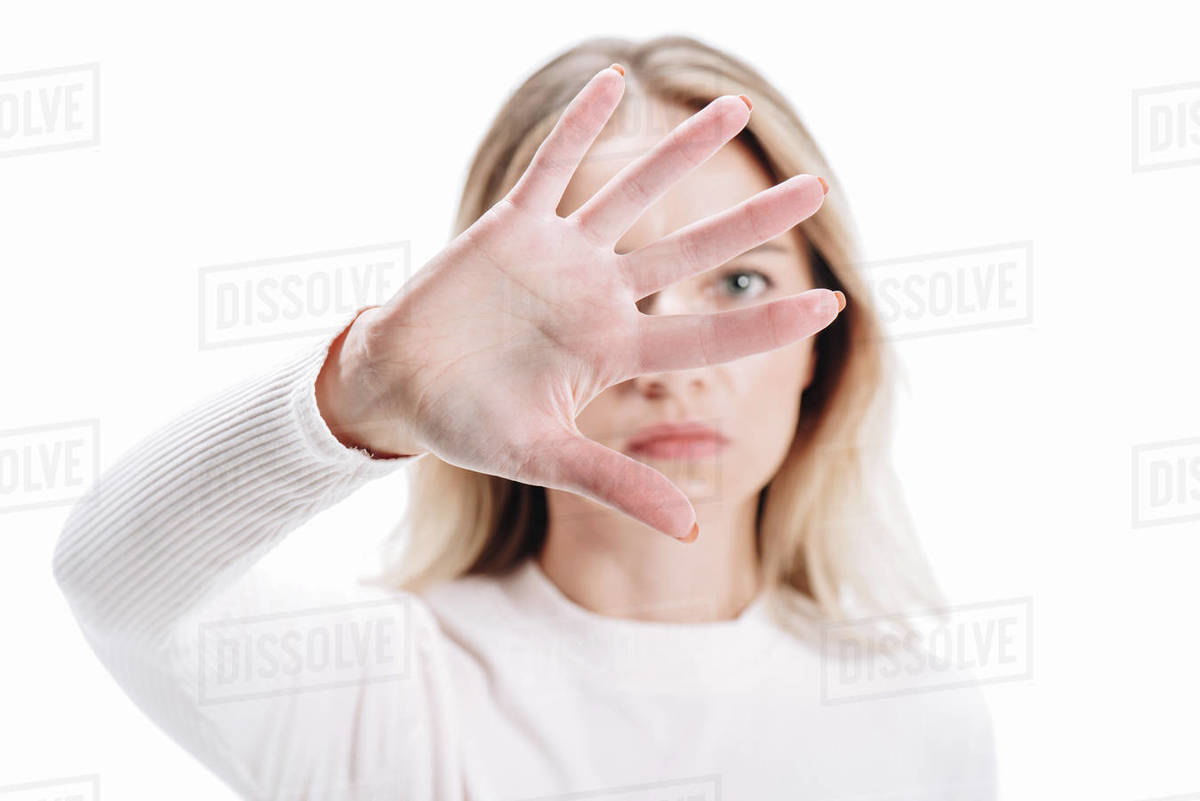 Blonde woman showing stop sign and looking at camera isolated on white ...