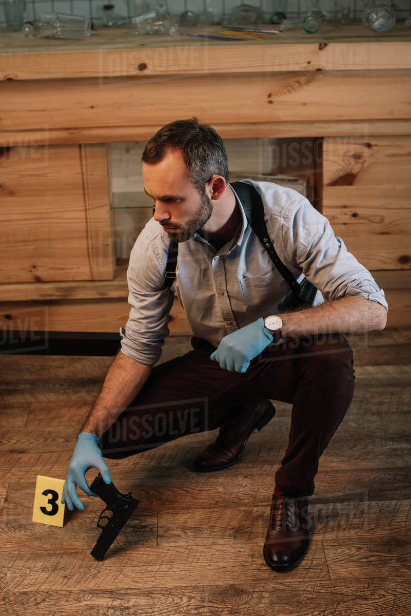 Focused male detective collecting evidence gun at crime scene - Royalty ...