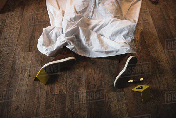 Cropped legs of dead body covered with white sheet at crime scene ...
