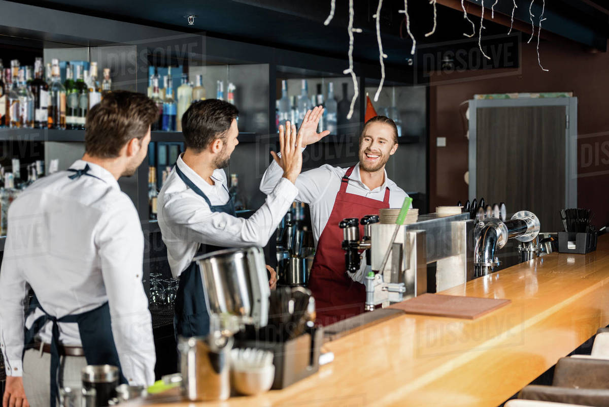 Handsome barmen in aprons high five at workplace - Royalty-free Stock ...
