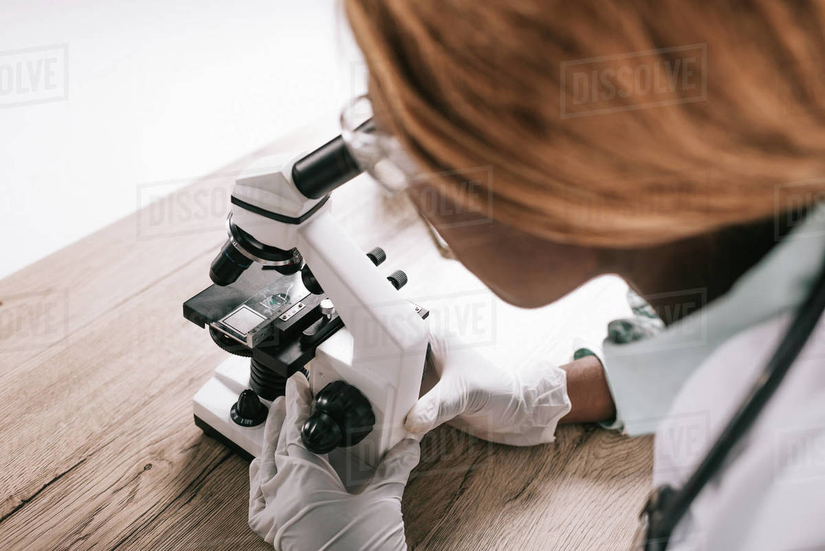 Cropped view of female African American scientist looking through ...
