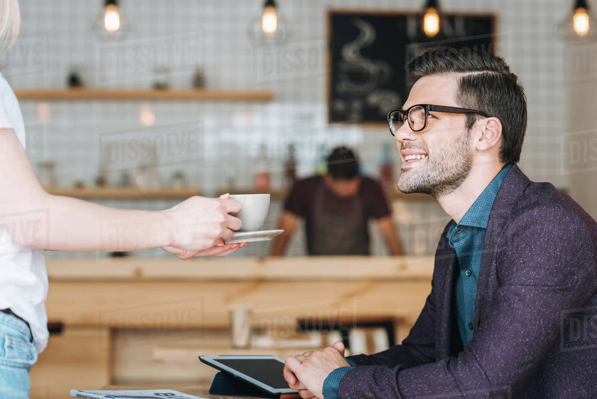 side view of waitress with order for businessman in coffee shop ...