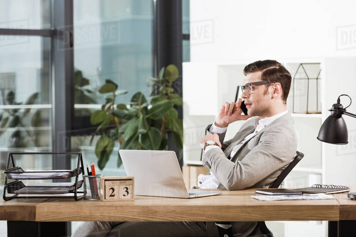 successful confident businessman talking by phone at workplace in ...