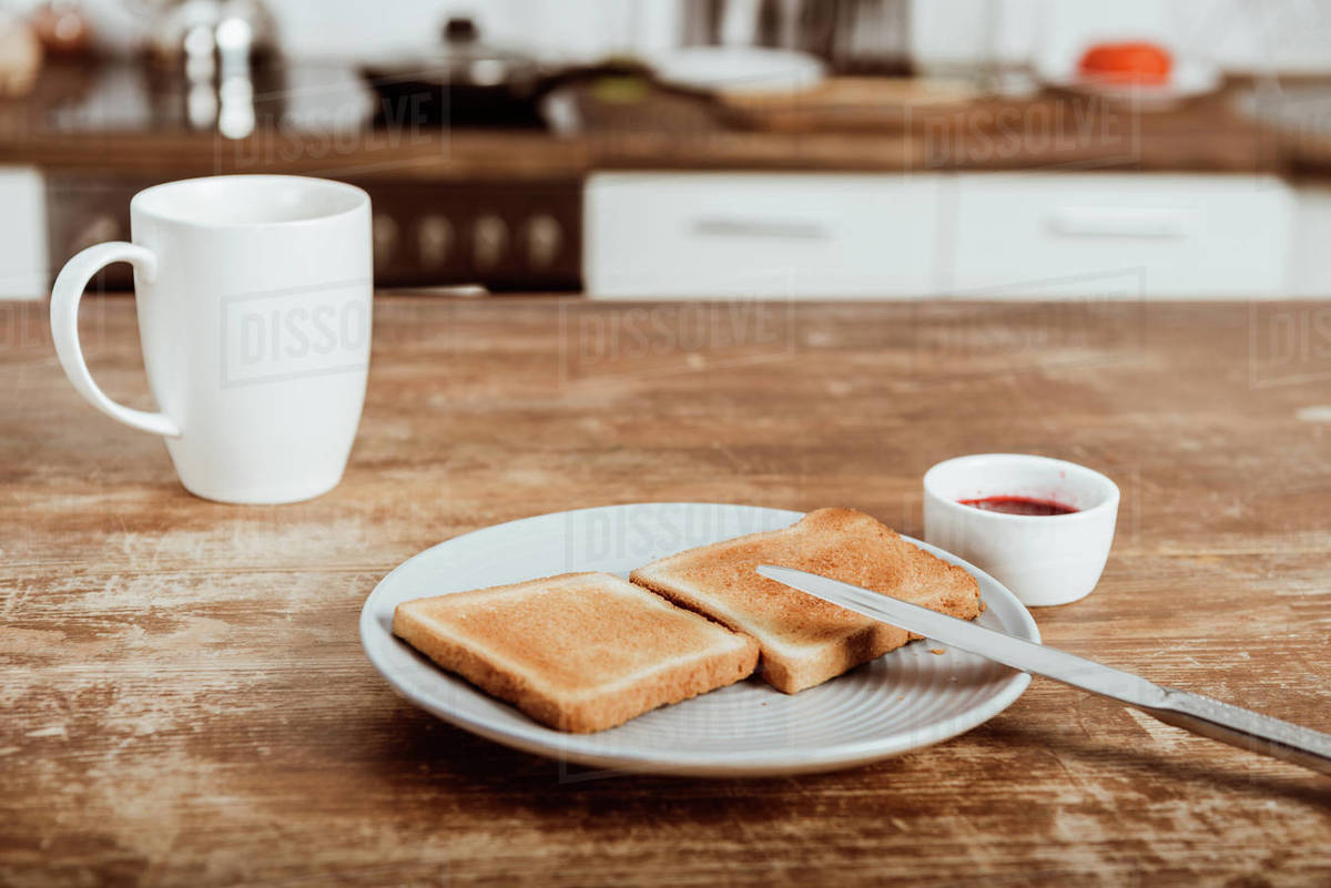 selective focus of toasts on plate, jam and coffee cup at table in ...