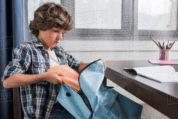 Side view of caucasian little boy packing backpack for school - Stock ...