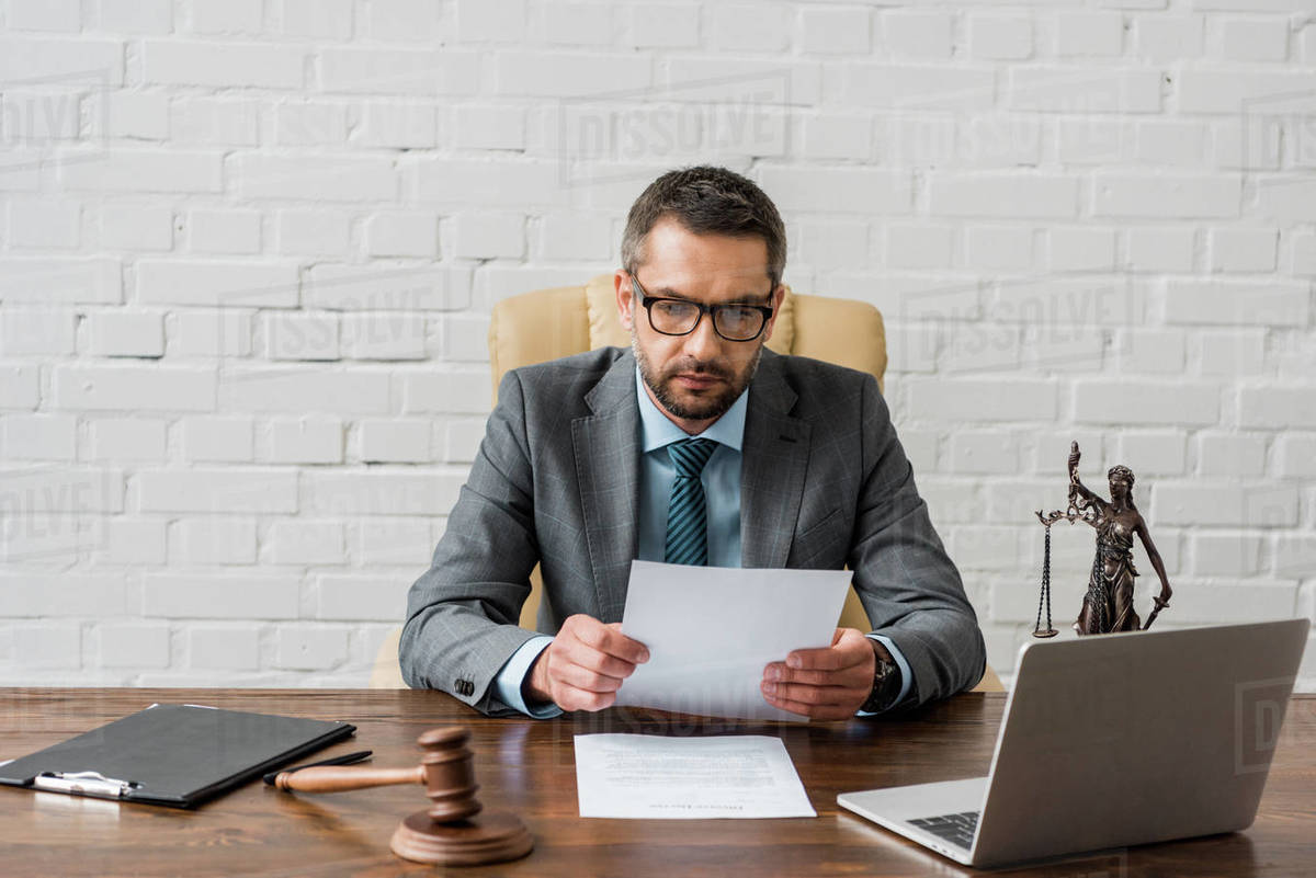 Serious male judge working with papers in office - Stock Photo - Dissolve