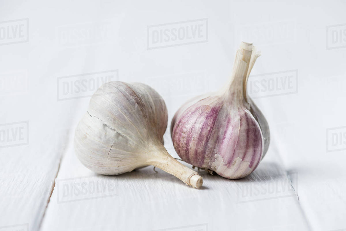 Two garlic heads on white wooden table - Stock Photo - Dissolve
