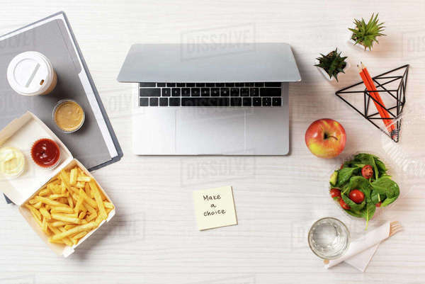 Top view of laptop, paper with inscription make a choice and junk food ...