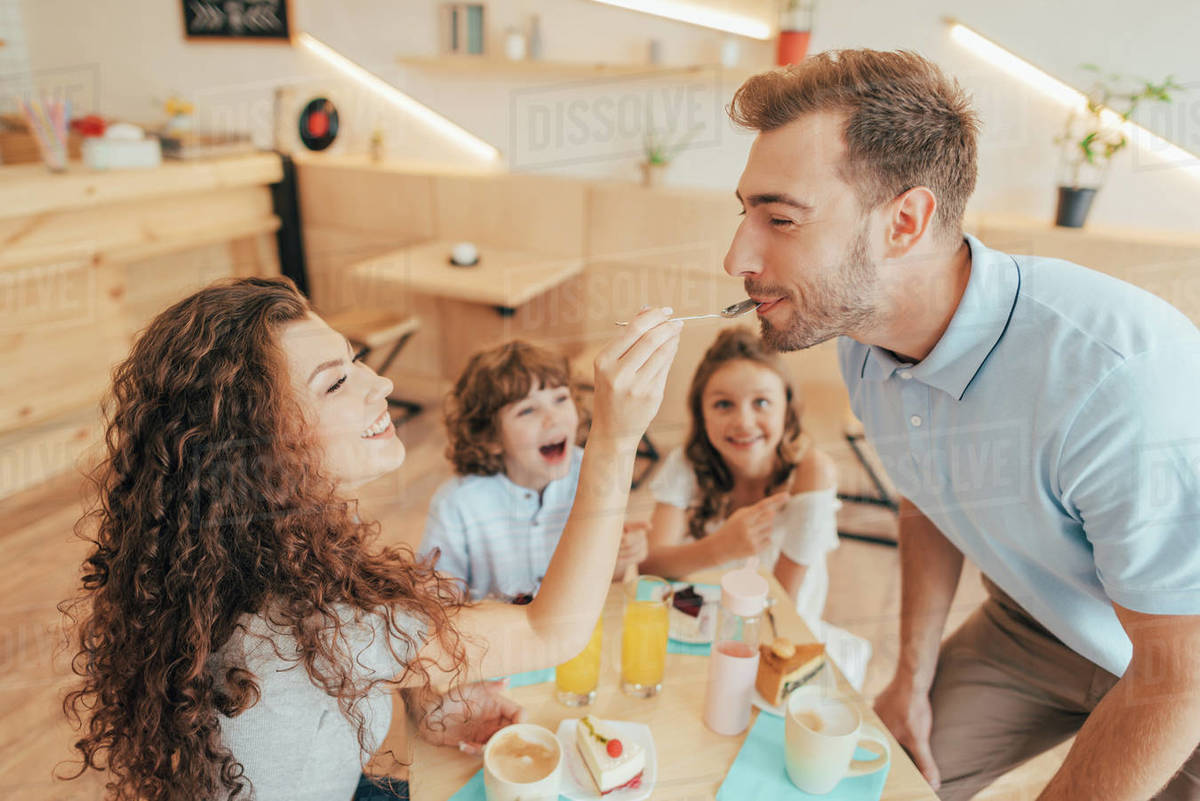 beautiful young family eating sweets in cafe with modern trendy ...