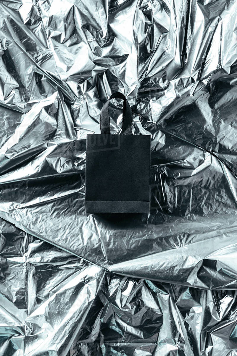 Top view of blank paper bag on silver wrapping paper background, black ...