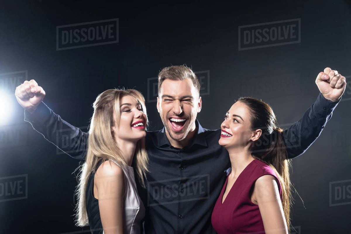 Happy celebrating man and women looking at camera on black - Royalty ...