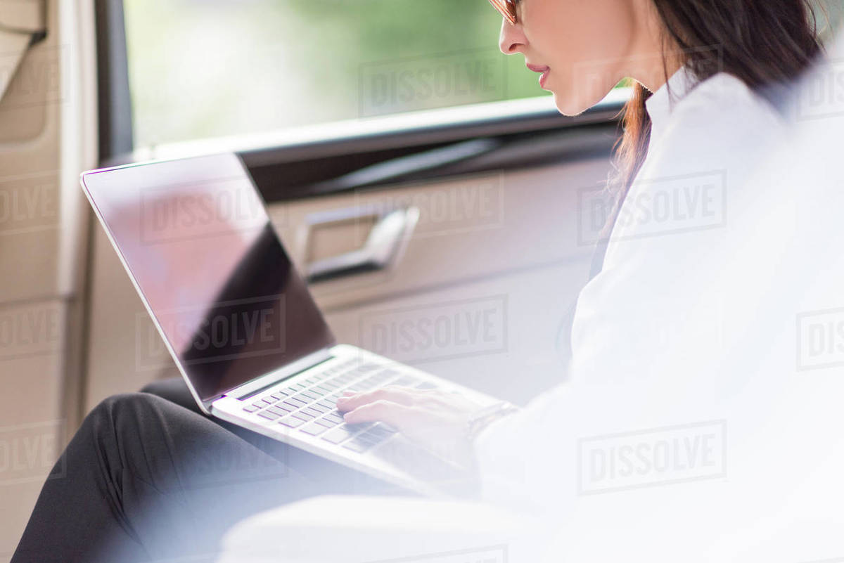 Cropped shot of woman sitting in a backseat of a car and using her ...