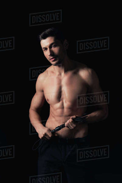 Shirtless man looking at camera and holding leather flogging whip ...