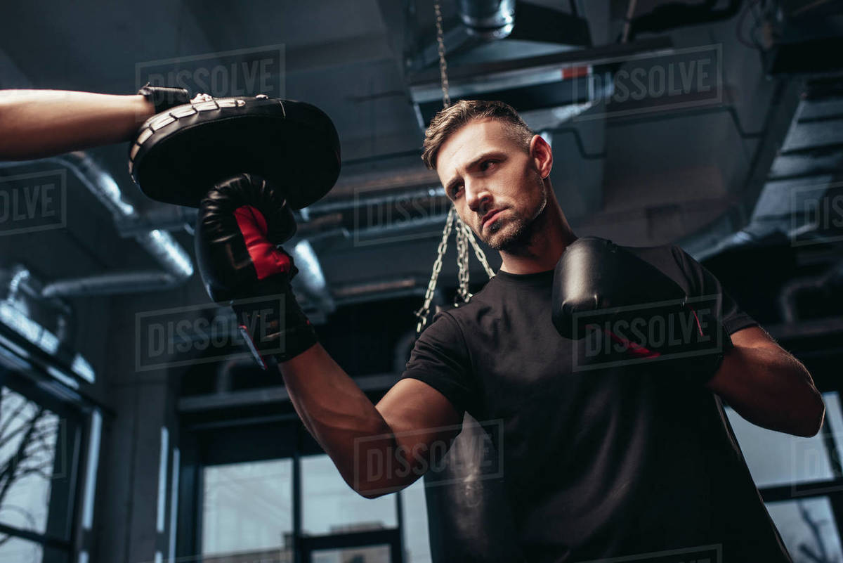 Low angle view of handsome boxer exercising with trainer in gym - Stock ...
